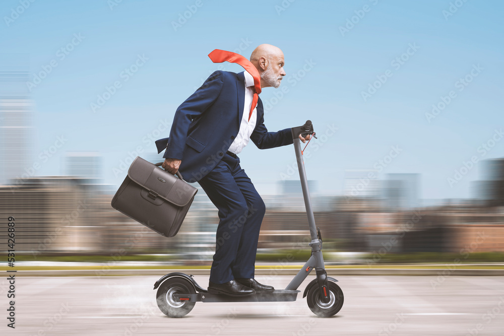 Foto Stock Corporate businessman riding a scooter | Adobe Stock