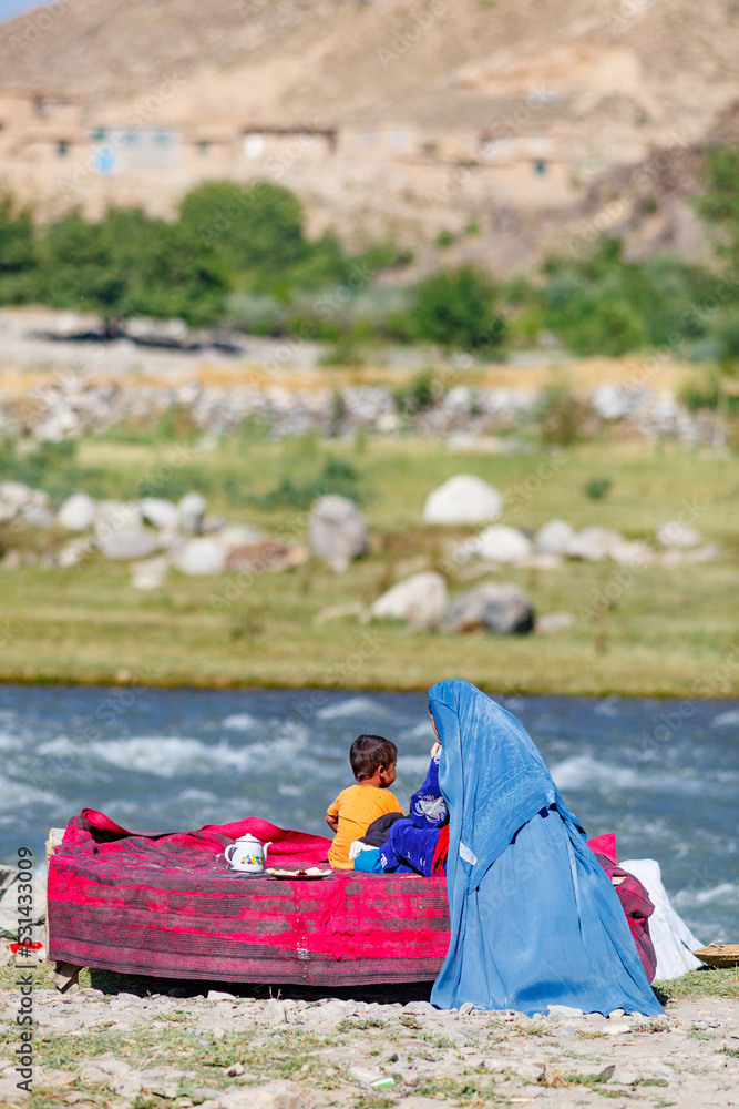 Afghan woman wearing a blue burka (burqa) and her son having tea in the ...