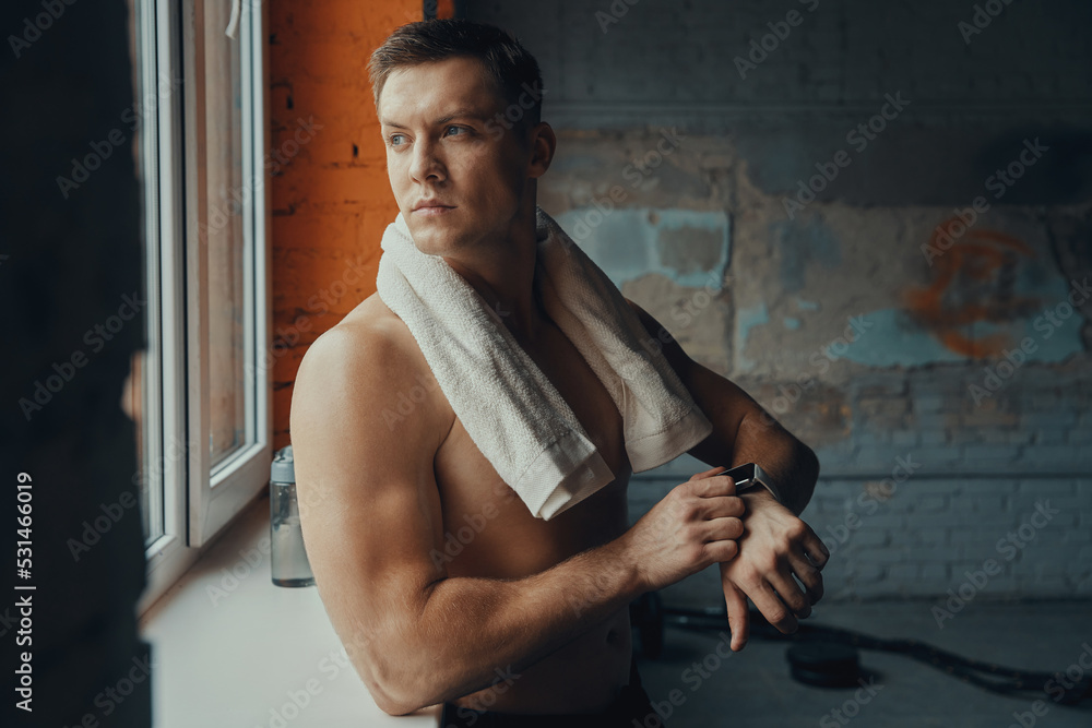 Handsome muscular man wearing smart watch while standing near the ...