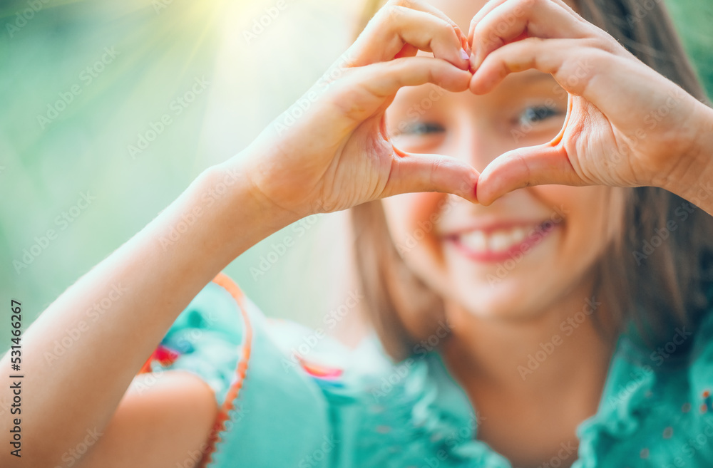 Cute child, happy little girl showing heart gesture and smiling outdoor ...