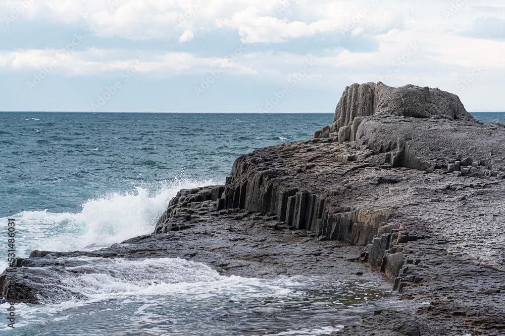 rocks formed by columnar basalt among the sea surf, Cape Stolbchaty on ...