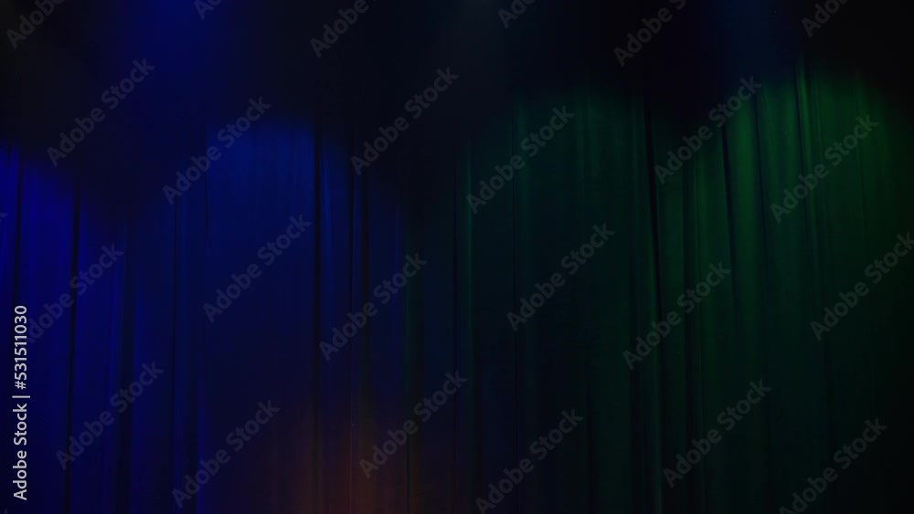 Blue velvet curtain with multicolored spotlights in theatre during ...