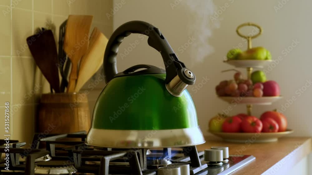 A green teapot boiling on a gas stove over an open flame. Kettle with ...