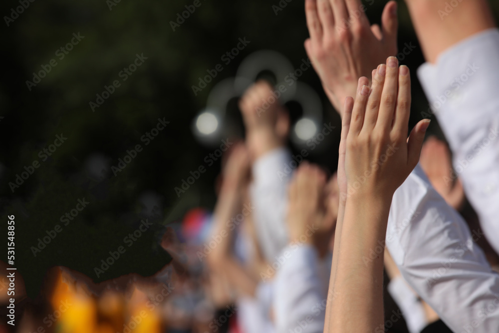A group of young people with their hands up and clapping in a gesture ...