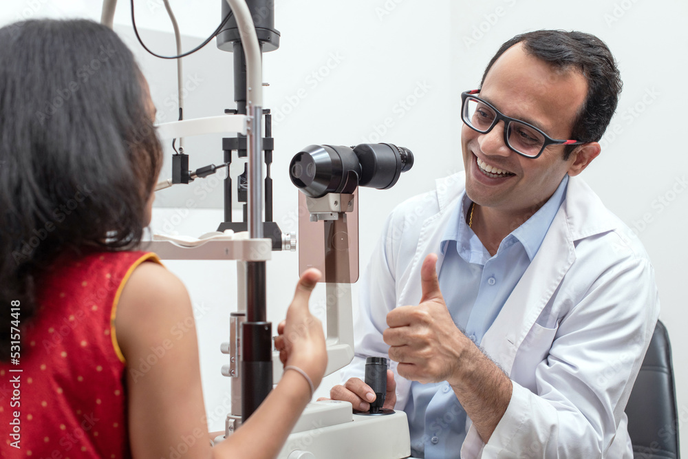 Indian girl and optometrist doing eye test with slit lamp in modern ...