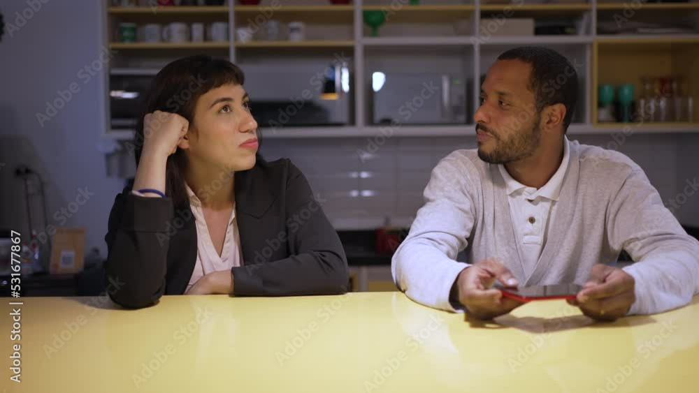 Two work colleagues in conversation at office kitchen table casually ...