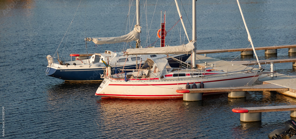 Sloop rigged sailboat (for rent and sale) moored to a pier in a yacht ...