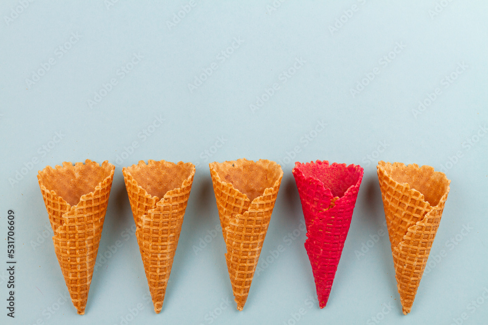 Red ice cream cone waffle amoung ordinary ones. Blue pastel background ...