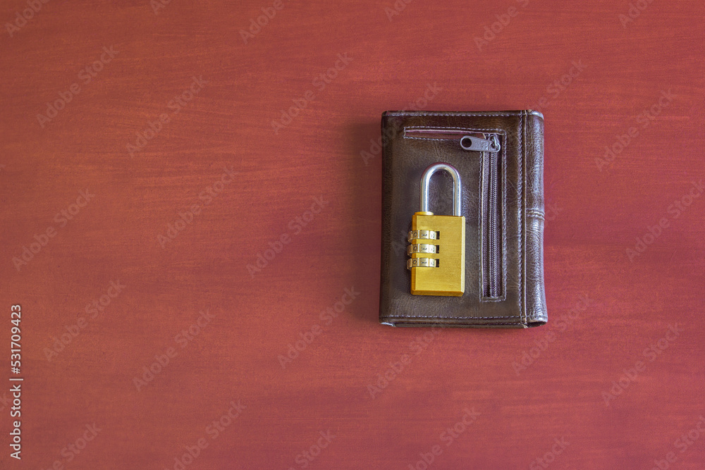 An isolated old leather wallet with a numeric closed gold padlock on ...
