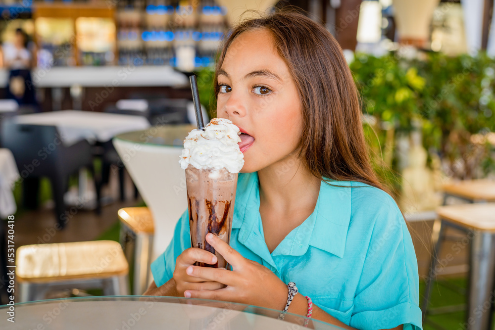 Beautiful child kid girl eating a chocolate shake in a restaurant. Cold ...