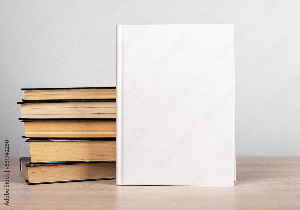 Book mockup and novels stack at wooden table. Template with white blank ...
