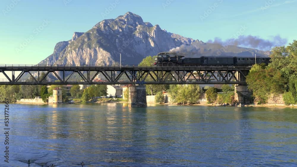 ancient steam locomotive crossing an ancient iron bridge over a river ...