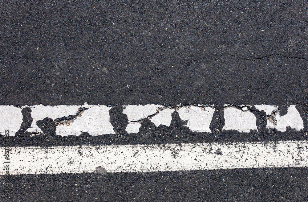 White center line of an asphalt road with the flaking old line and a ...