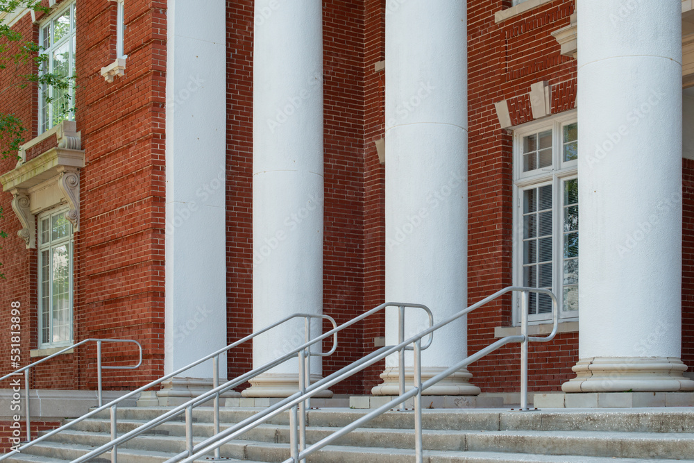 Four large white round columns at the facade entrance to a red vintage ...
