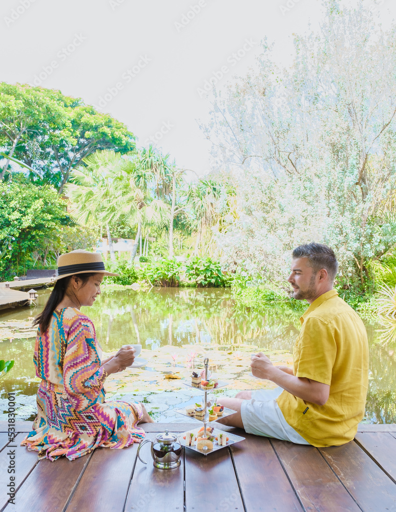 Afternoon tea at a water pond, high tea in a tropical garden in ...