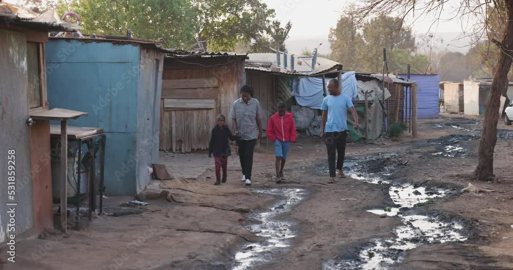 Poverty. Inequality. Poor Black African family walking in a typical ...