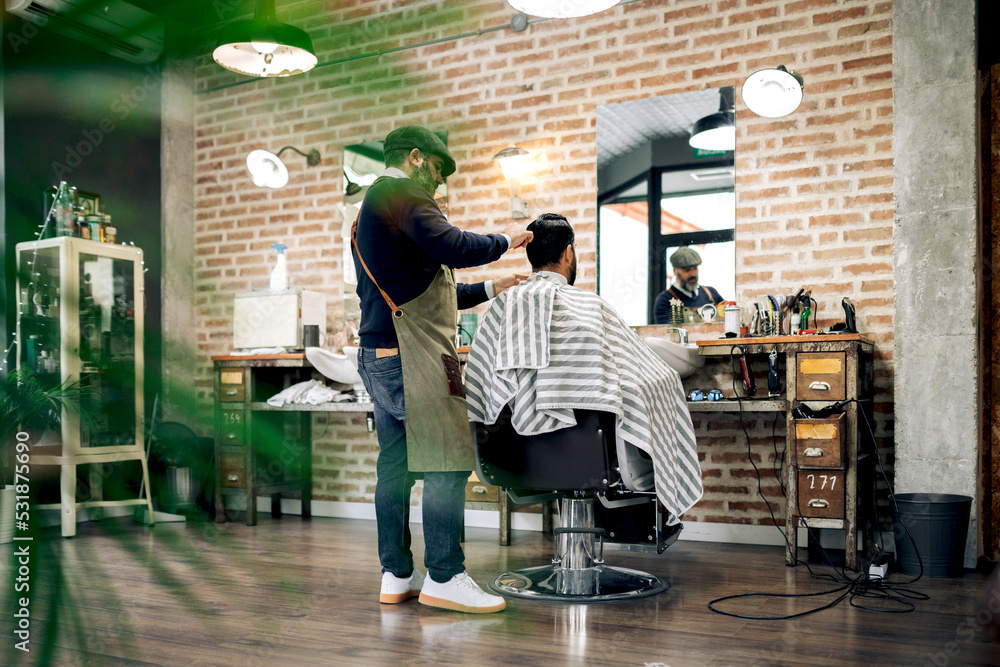 Crop barber brushing hair of client in salon Stock Photo | Adobe Stock