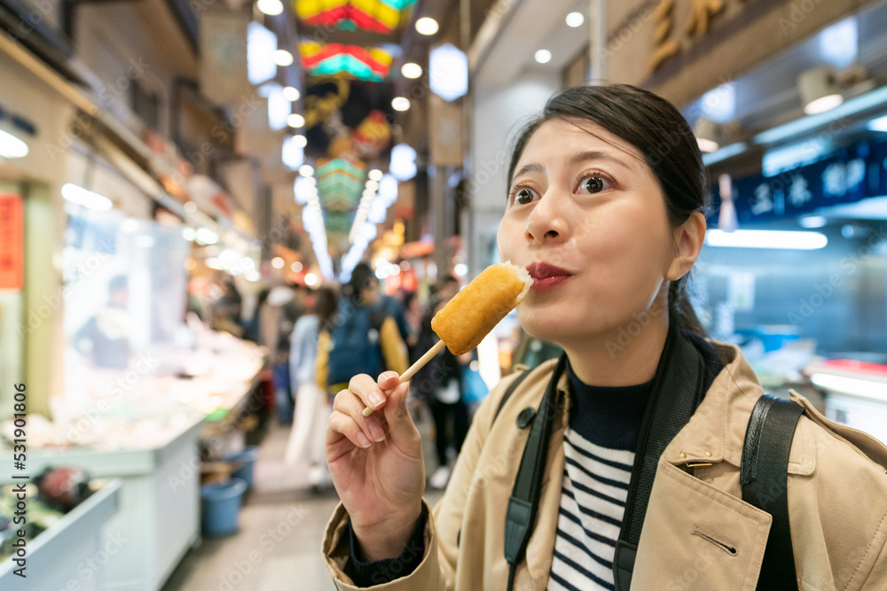 portrait of amazed asian Chinese girl visitor eating yummy oden stick ...