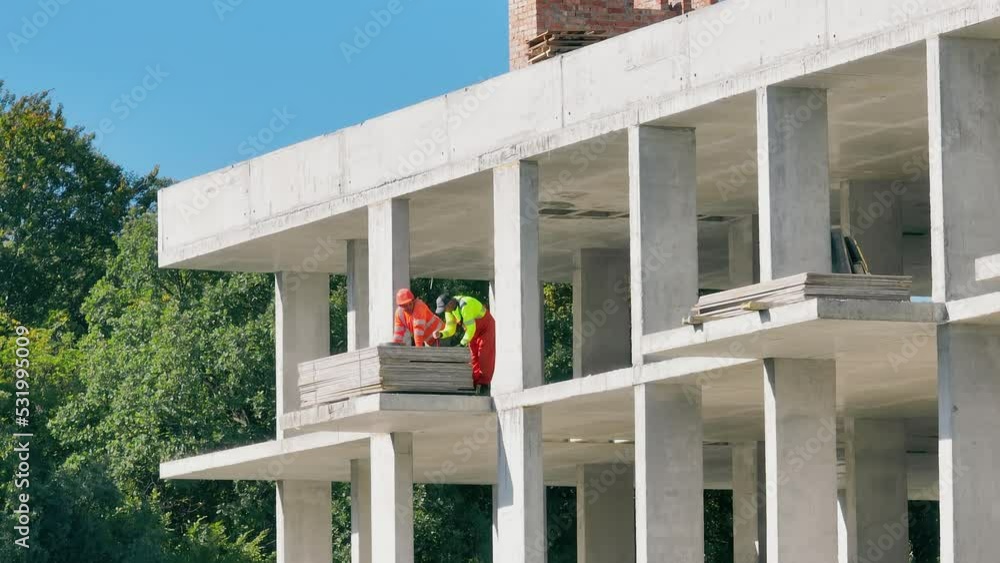 Builders are unpacking a large cargo during the construction of a house ...