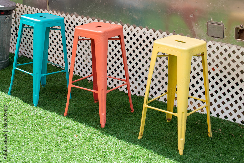 Three colorful iron metal stackable bar stools, blue, peach, and yellow ...