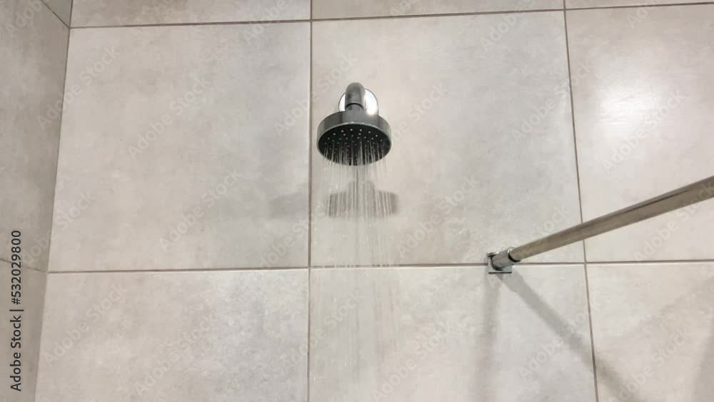 Water flows from the shower metal nozzle and faucet in a modern shower ...