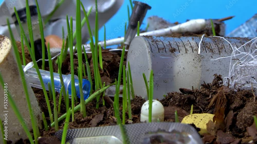 Macro footage of polluted earth by medical waste and growing grass in ...