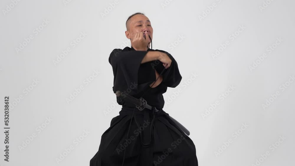 Japanese man traditional dress, black kimano katana samurai sword strikes, takes out scabbard ...