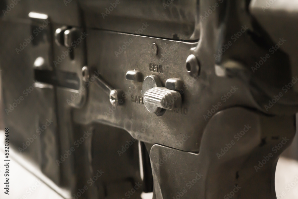Close-up shot of selective fire of khaki camouflage M4 assault rifle ...