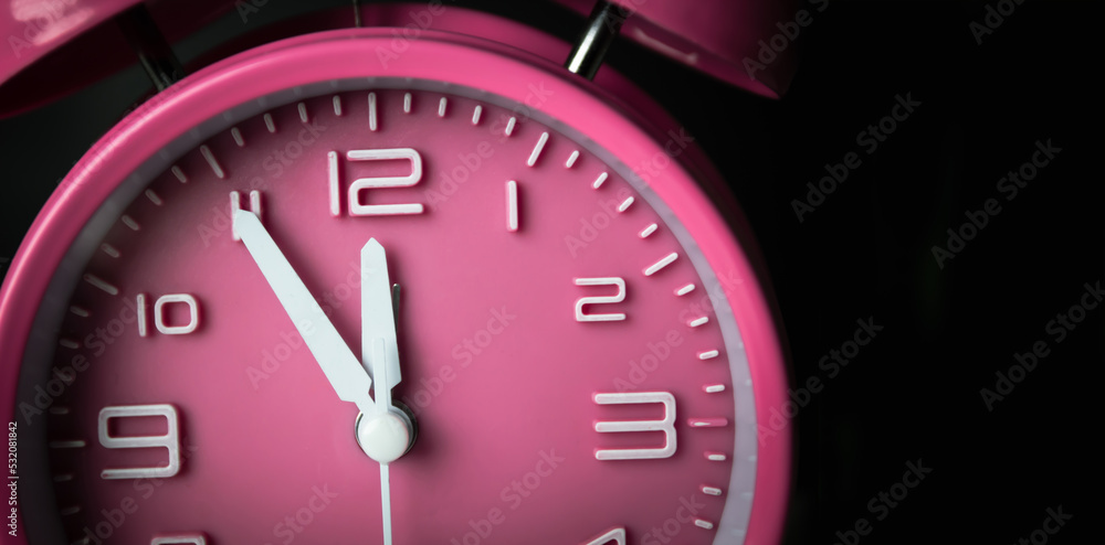 Pink alarm clock setting at five before noon or midnight. Time ...
