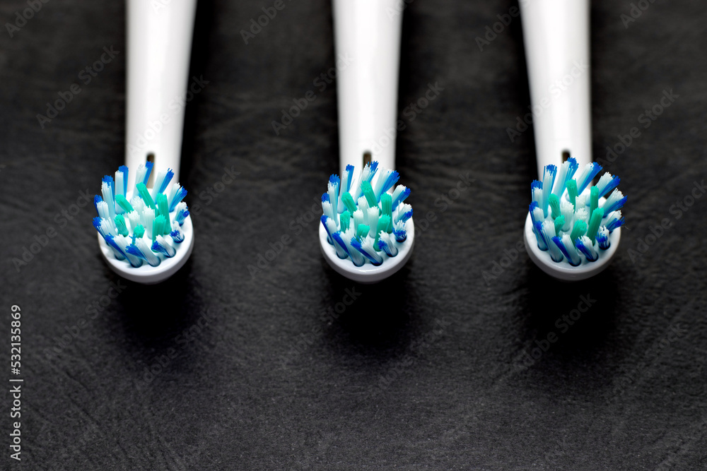 some 3 electric toothbrush heads isolated on black dark structured ...