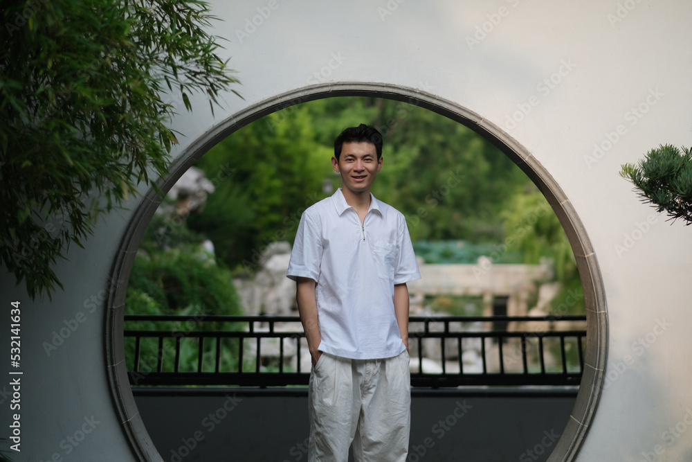 cute smiling Chinese young man at moon gate in traditional Chinese ...