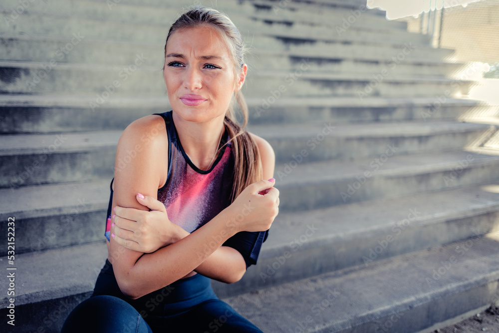 Shot of an attractive young woman suffering from a shoulder injury ...