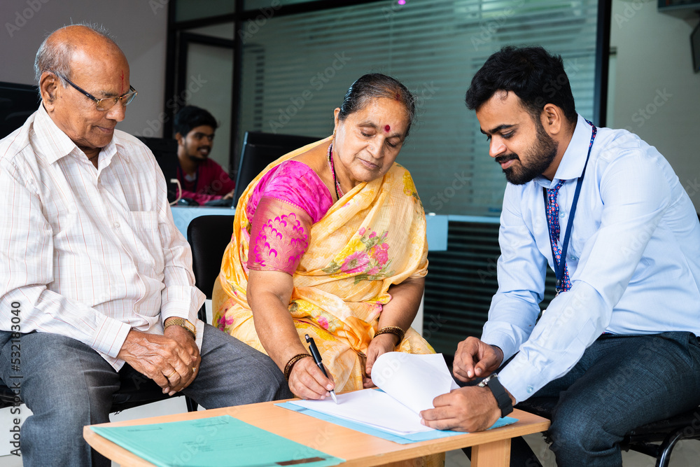 bank employee taking sign from retired senior couple at office for ...
