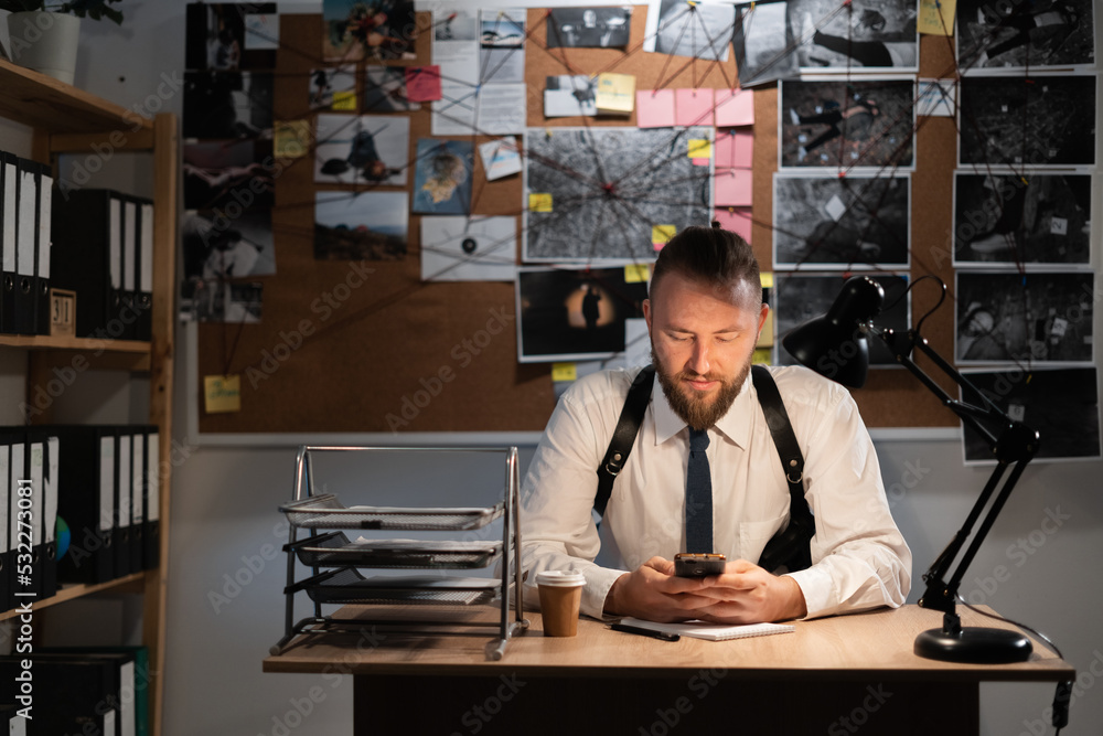 male detective is sitting in the office flipping through the news feed ...