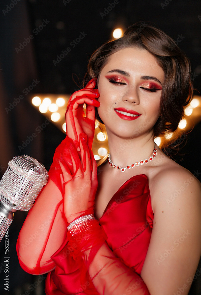 Sexy young girl singer sings into a silver retro microphone in a red ...