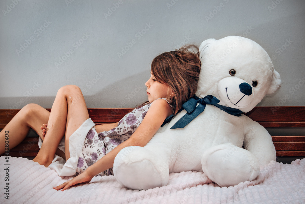 Upset sad child. Little girl with a big teddy bear. Problems with ...
