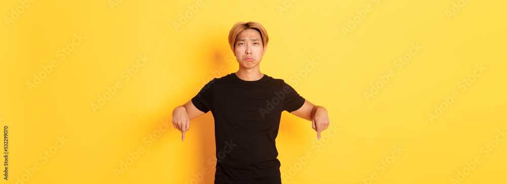 Portrait of disappointed gloomy asian guy, pouting upset and pointing ...