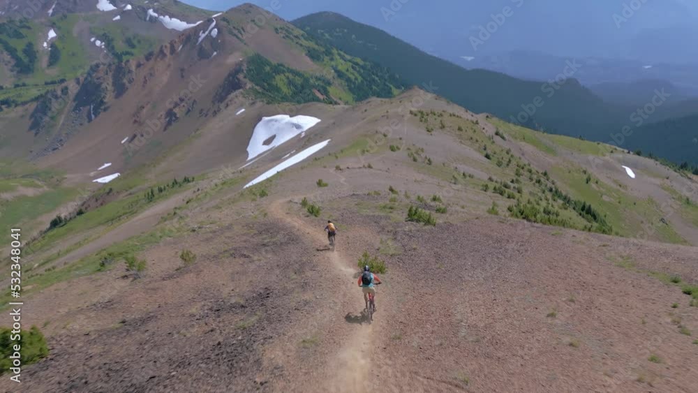 4K video of two mountain bikers riding fast on high alpine ridgeline in ...
