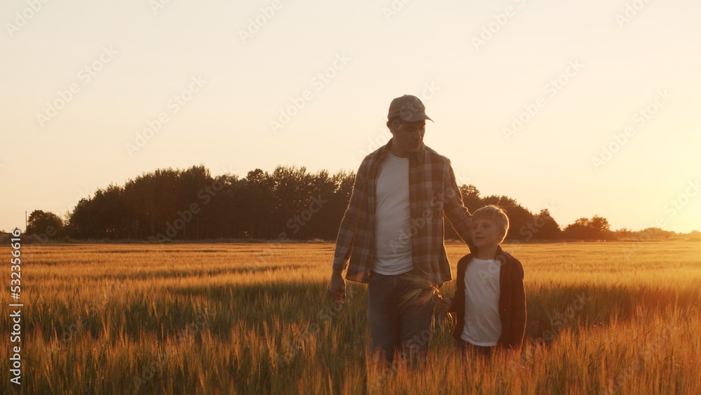 Farmer and his son in front of a sunset agricultural landscape. Man and ...