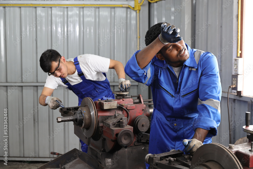 Tired heat and hot technicain mechanic man in uniform using metal lathe ...