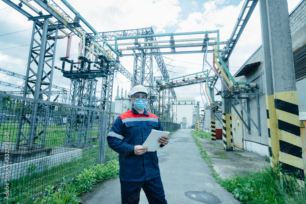 A masked power engineer during a pandemic inspects the modern equipment ...