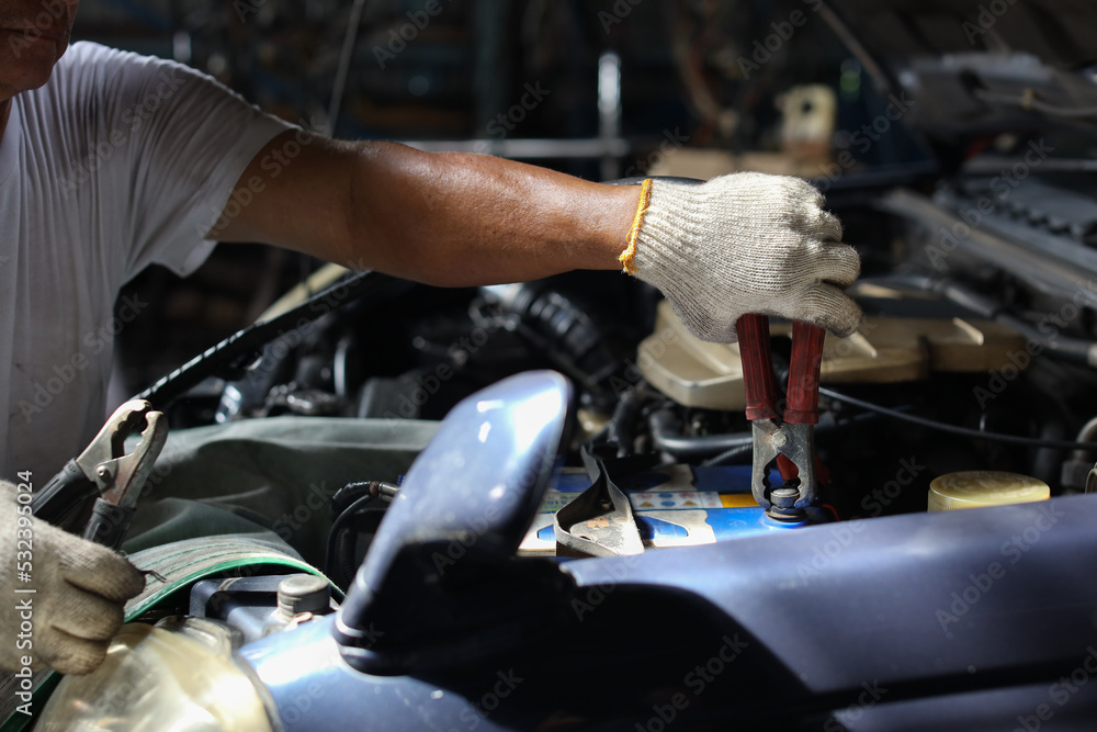 Man mechanic hands in half uniform charging battery a car with ...