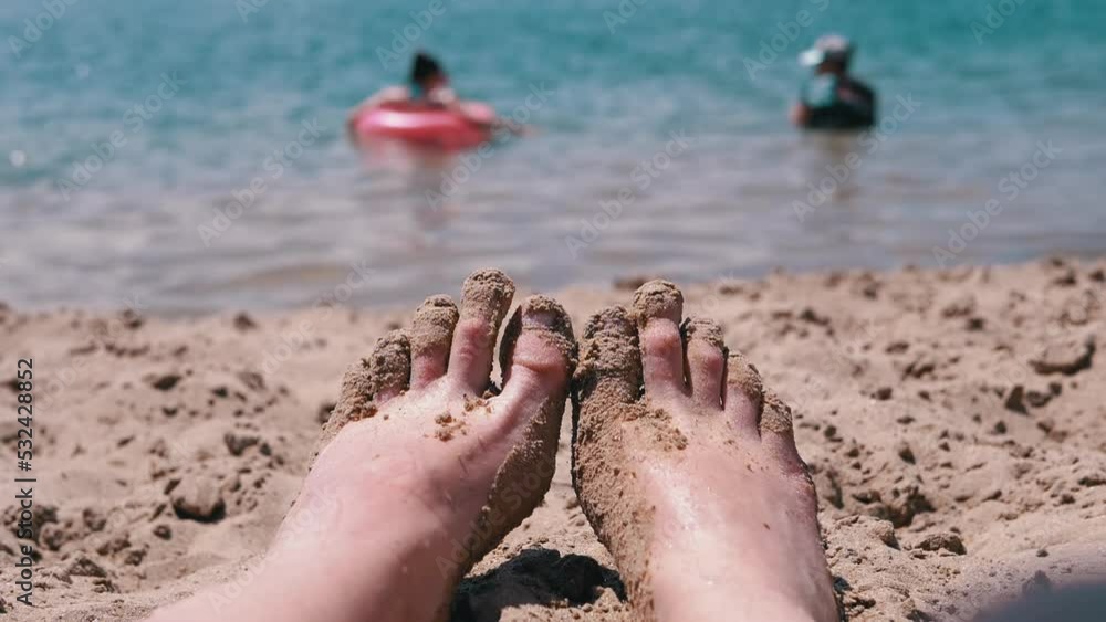 POV Female Wet Feet in Sand Lying on a Sandy Beach in Sun Glare near ...