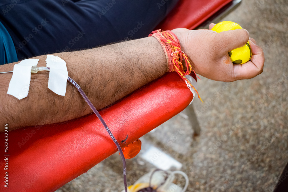 Blood donor at Blood donation camp held with a bouncy ball holding in ...