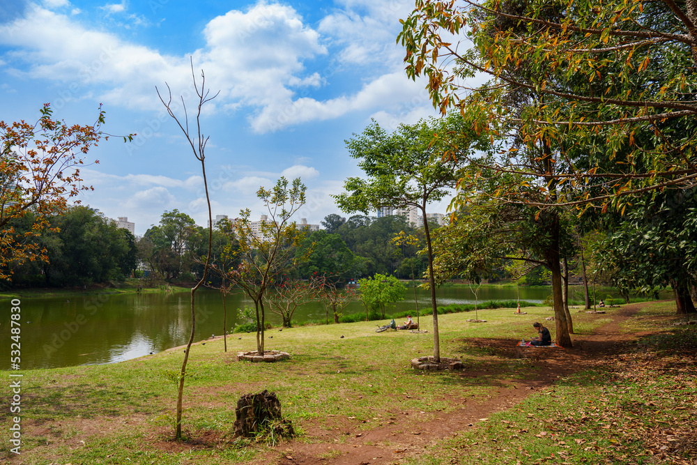 Paisagem de um parque em lindo dia de Sol com as pessoas relaxando ...