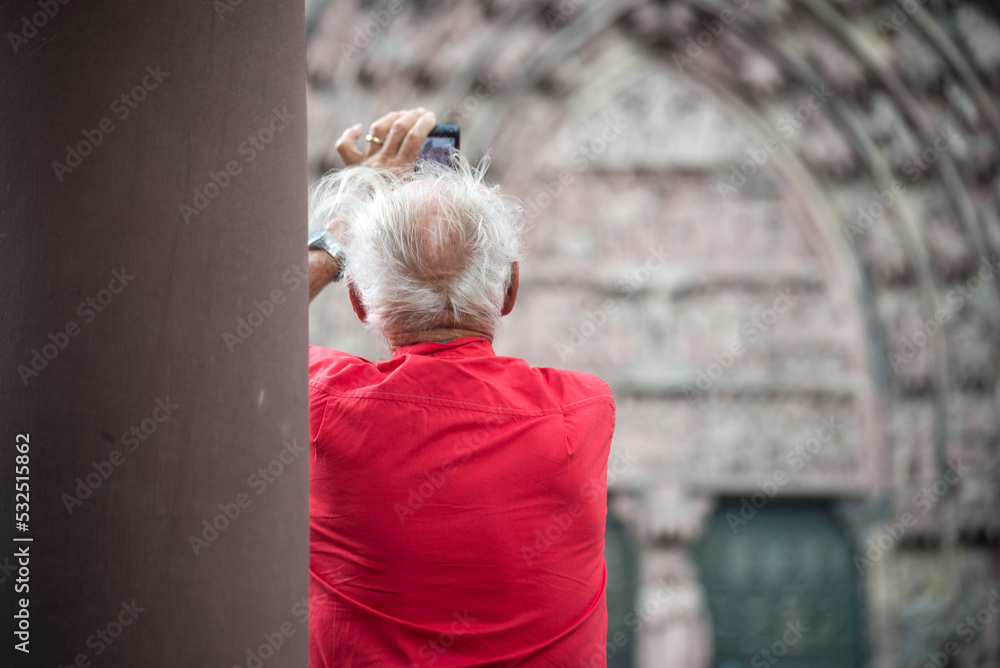 portrait on back view of old man taking a photo with his smartphone in ...