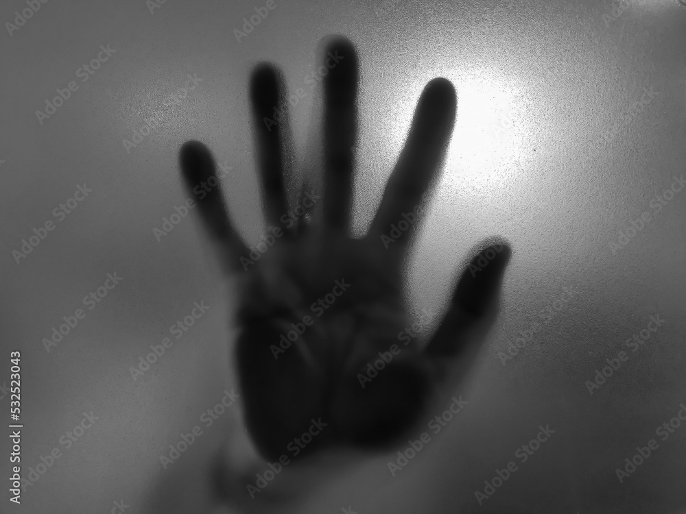 Black and white shadow image of hand behind the frosted glass sign of ...
