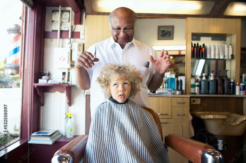 Barber getting ready to cut cute little boy's hair at barbershop Stock ...