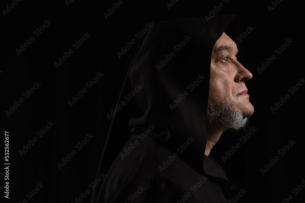 profile of mysterious monk in dark hood isolated on black. Stock Photo ...