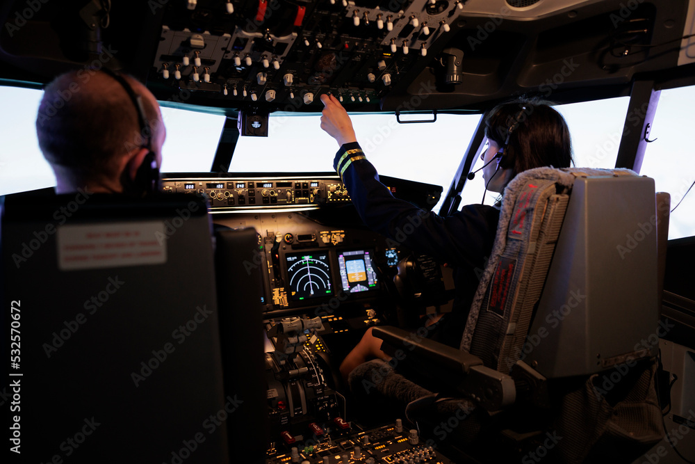 Female pilot assisting captain to takeoff and fly airplane, using ...